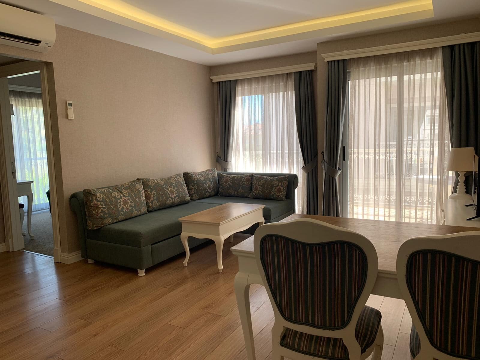 Uma sala de estar moderna com um sofá seccional, uma mesa de centro de madeira e cadeiras listradas.