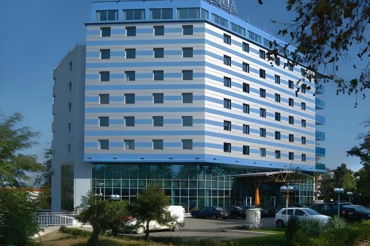 Um hotel de vários andares com design moderno, exibindo uma placa grande com a inscrição 'HOTEL AQUA' no topo.
