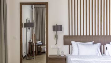 Quarto de hotel com cama, luminárias, mesa de cabeceira, espelho e vista para o corredor.