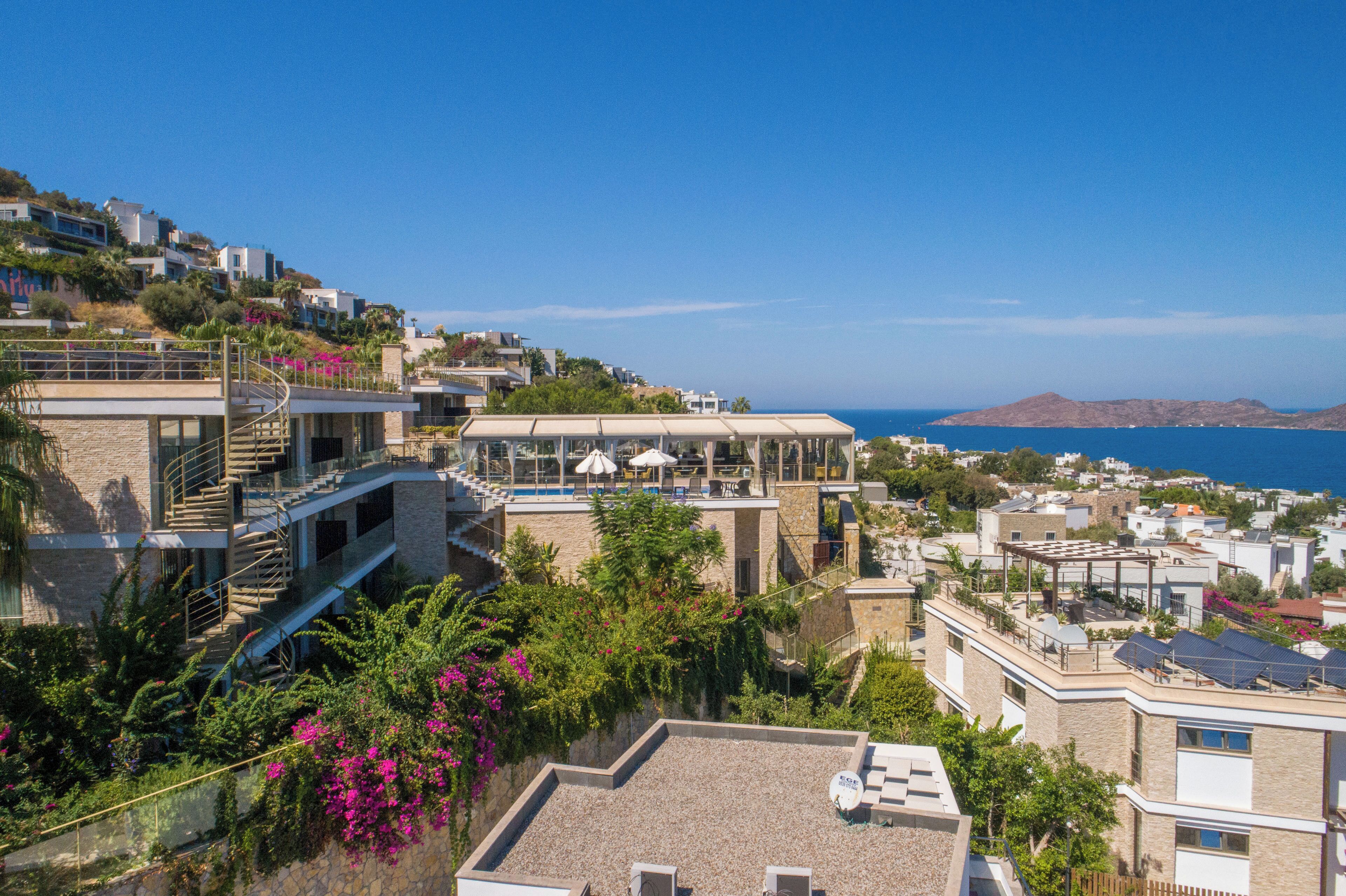 Zona residencial costeira com edifícios modernos, uma escadaria imponente e vista para o mar.