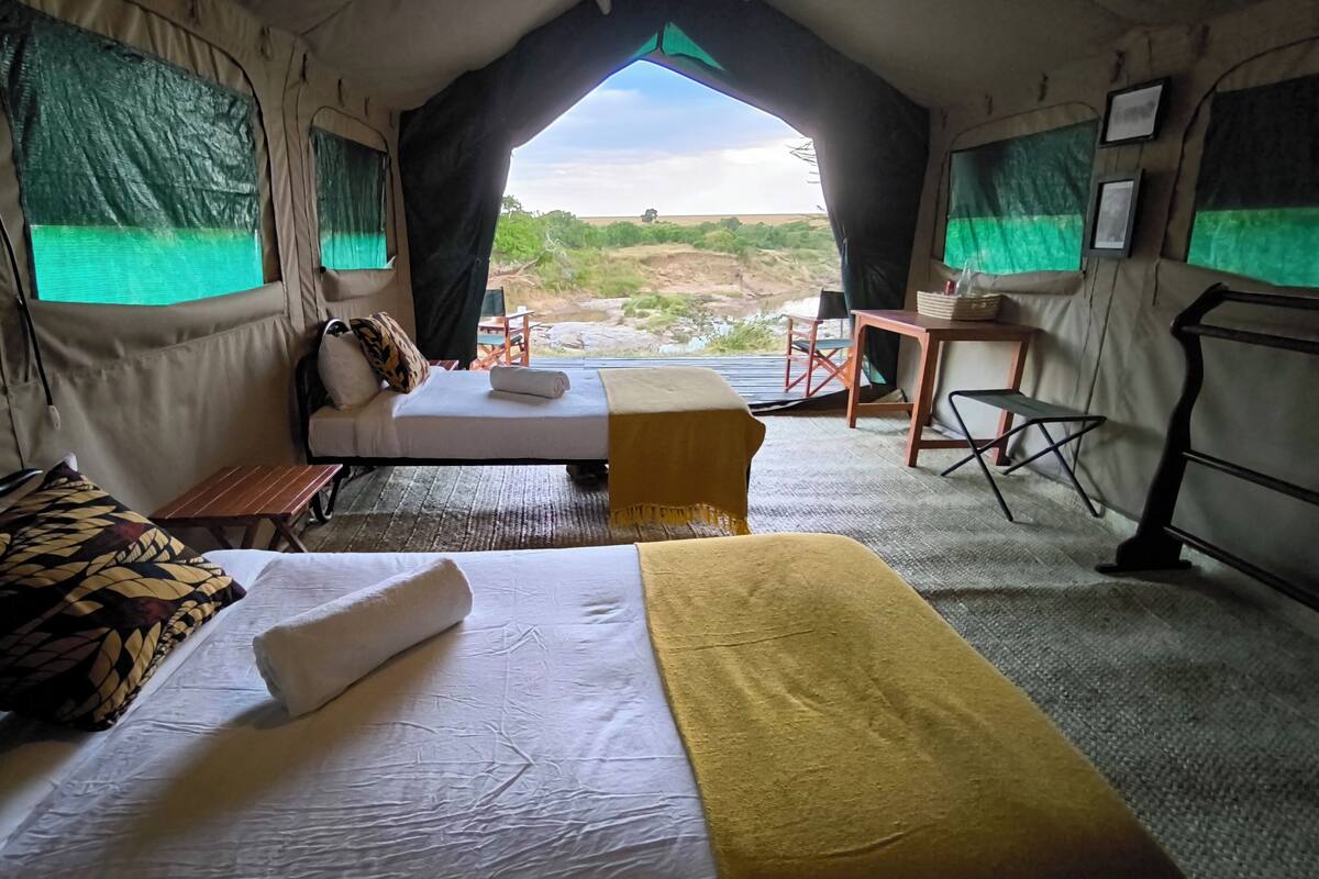 Um quarto tipo tenda com uma cama, uma mesinha e uma cadeira.