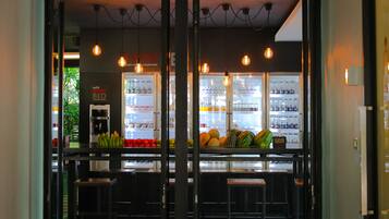 Interior de restaurante com estação de reabastecimento de água, área de estar e refrigerador de bebidas.