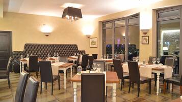 Restaurante com teto alto, assentos acolchoados e mesas postas para refeições.