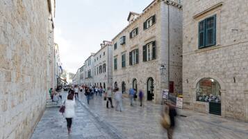 Uma rua de pedra com edifícios históricos, alguns com lojas e outros com janelas em arco.