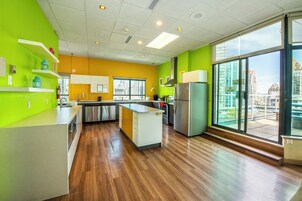 Uma cozinha moderna com piso de madeira, uma ilha central e uma grande janela com vista para a cidade.