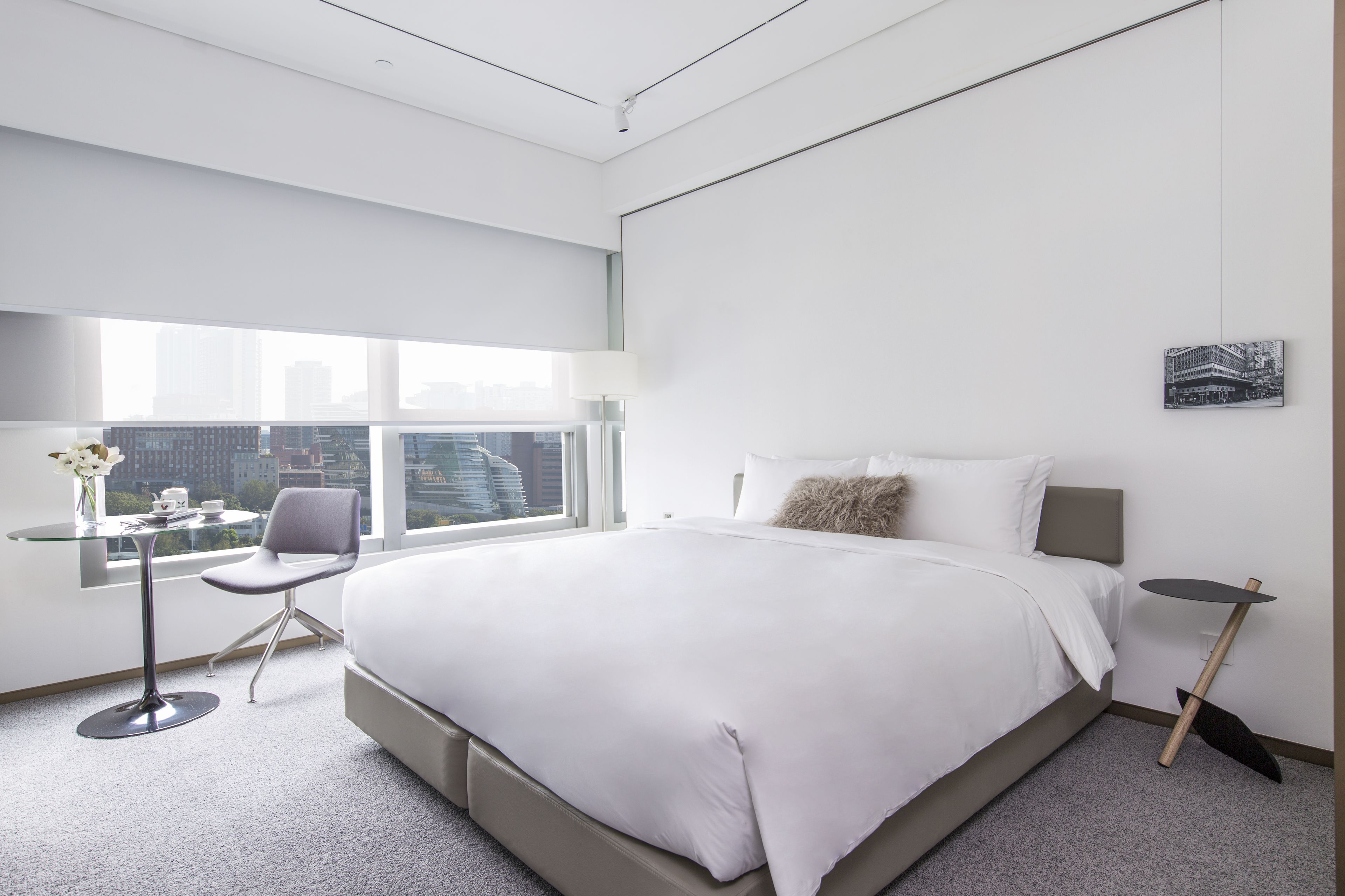 Quarto de hotel moderno com uma cama grande, uma escrivaninha e uma cadeira.
