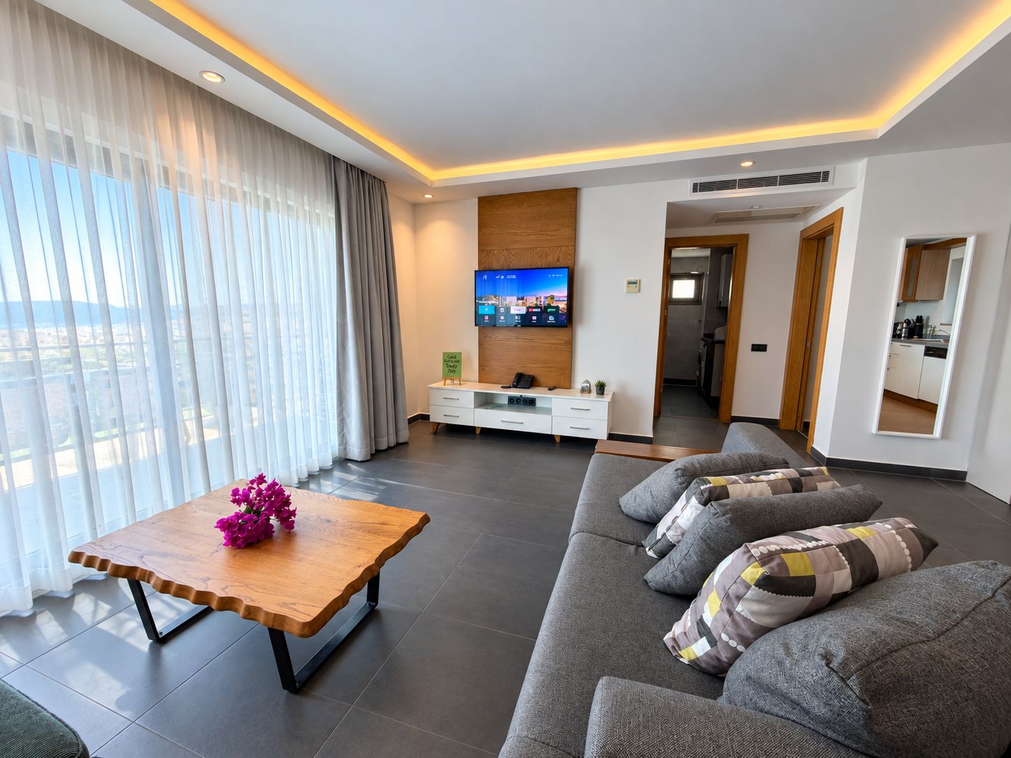 Uma sala de estar moderna com um sofá, uma mesa de centro de madeira e uma televisão.