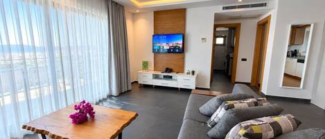 Uma sala de estar moderna com um sofá, uma mesa de centro de madeira e uma televisão.