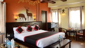 Quarto de hotel com uma cama grande, uma escrivaninha com abajur e uma parede com um mural de veado.