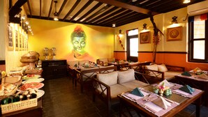 Restaurante com mobiliário de madeira, um mural de Buda e um ambiente acolhedor.
