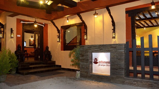Entrada de um hotel boutique com fachada de pedra, vigas de madeira e uma placa.