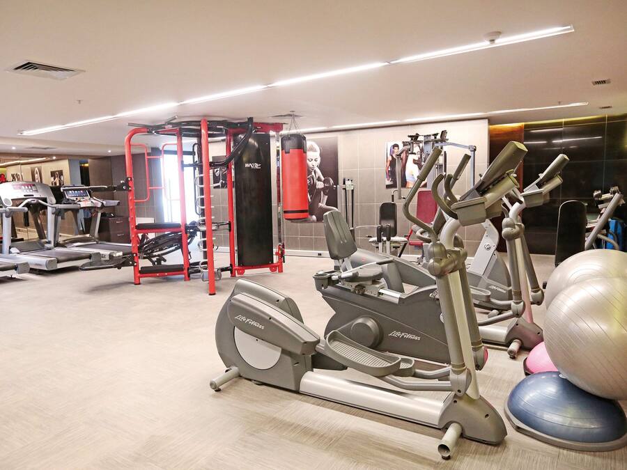 Uma academia com esteiras, elípticos e bolas de exercício.