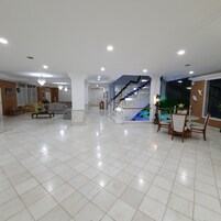 Uma sala de estar ampla com escada para uma varanda, um espaço de refeições com cadeiras e um lustre.