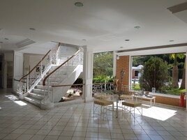 Um quarto amplo com escada branca, uma janela grande e piso ladrilhado.