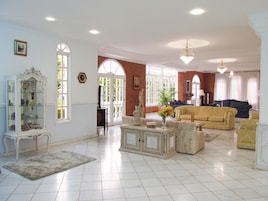 Uma sala de estar ampla com uma grande janela, lareira e um candelabro.