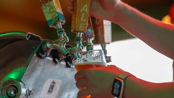 Uma mão servindo cerveja de uma torneira com a etiqueta 'PALE ALE'.