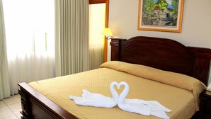 Quarto de hotel com uma cama, um quadro na parede e um abajur.