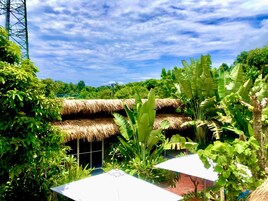 Um jardim exuberante com construções de palha e plantas tropicais.