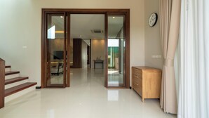 Um interior moderno com escada de madeira, porta de correr de vidro que dá para uma sala de jantar e um armário de madeira.