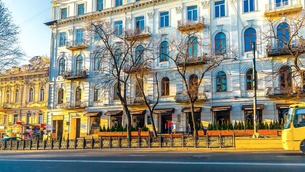 Um edifício de vários andares com estilo arquitetônico clássico, com janelas em arco e sacadas.