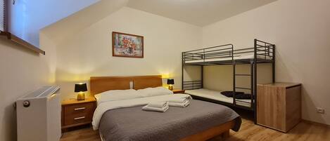 Quarto com uma cama beliche, escrivaninha, cadeira, luminária e um quadro na parede.