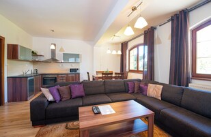Um espaço de estar moderno com cozinha, área de jantar e um amplo sofá modular.
