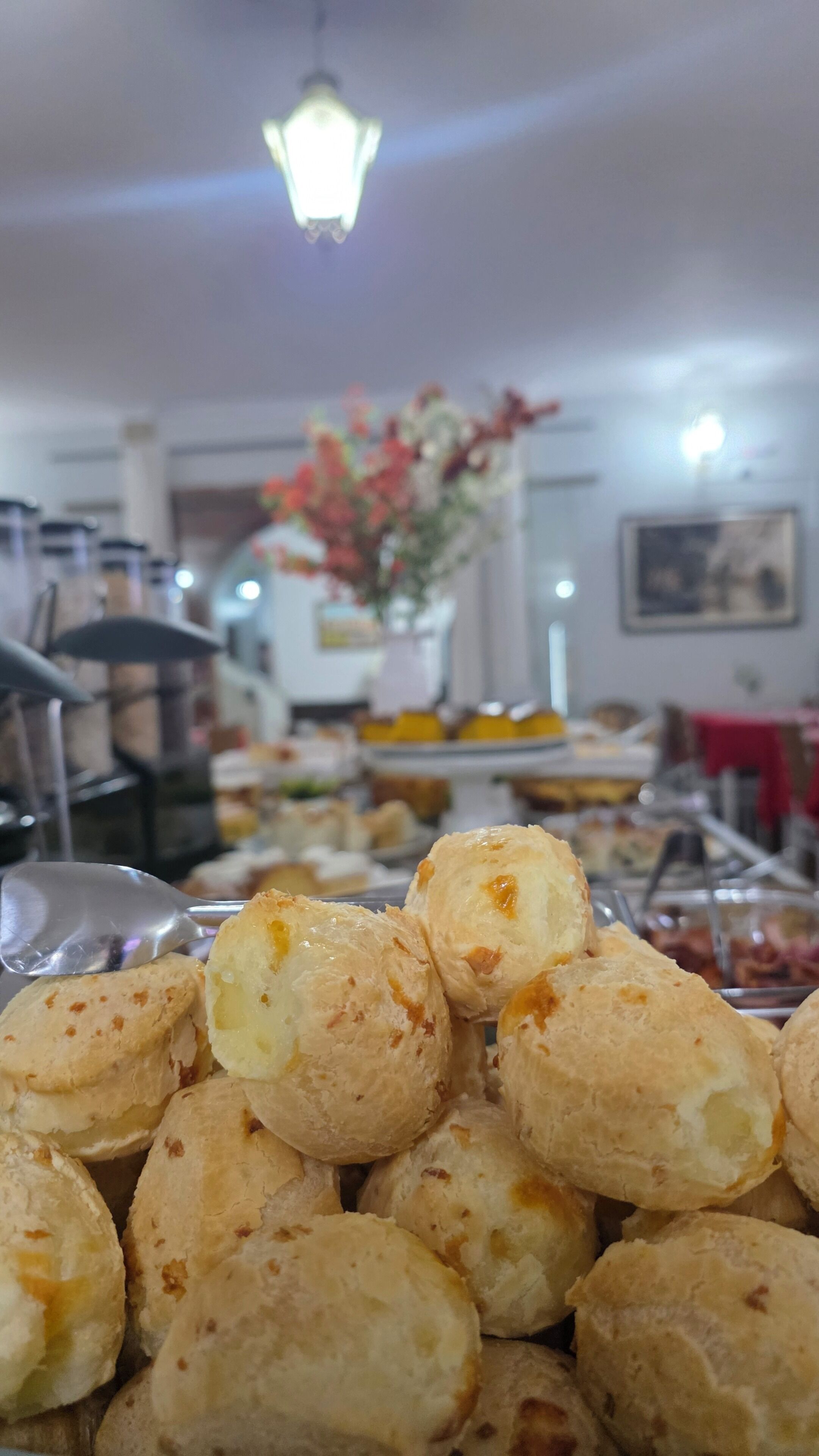 Buffet com diversos alimentos, incluindo uma pilha de pão de queijo.