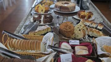 Um buffet com diversos pães e doces.