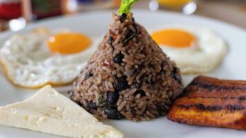 Um prato com arroz, dois ovos fritos, uma fatia de queijo e uma fatia de banana grelhada.