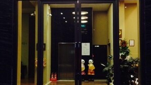 Entrada de hotel com tapete vermelho e placa de boas-vindas.