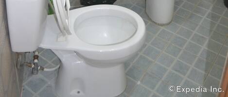 Casa de banho com sanita, lavatório e um contentor de lixo.