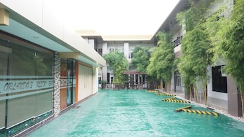 Um pátio com piscina, edifícios com fachada de vidro e árvores verdes.
