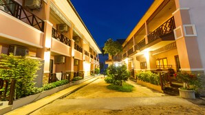 Um pátio com um jardim central, rodeado por edifícios com vários andares, varandas e aparelhos de ar condicionado.