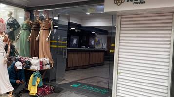 Zona de compras de hotel, com manequins exibindo vestidos e uma banca vendendo roupas.