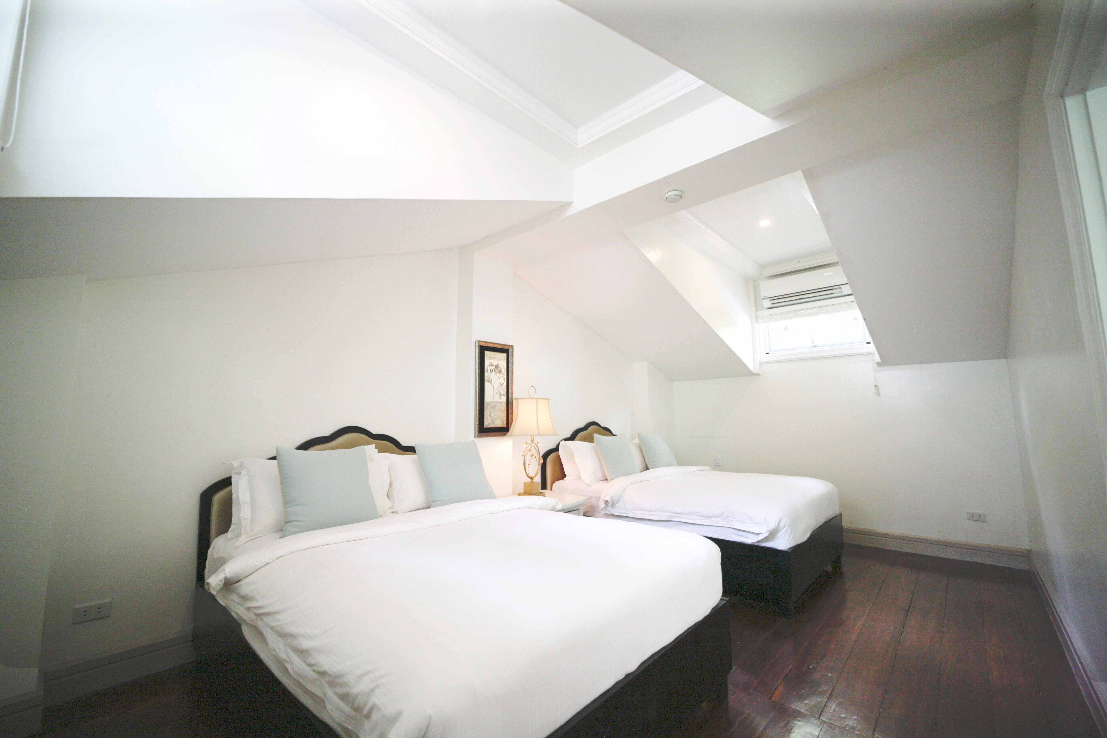 Quarto com duas camas, ventilador de teto e janela.