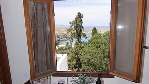 Uma área de refeições com mesa e cadeiras, uma janela com vista para a paisagem e um aparelho de ar condicionado sobre a janela.