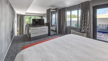 Quarto de hotel moderno com uma cama grande, televisão de tela plana, escrivaninha e vista para o exterior.