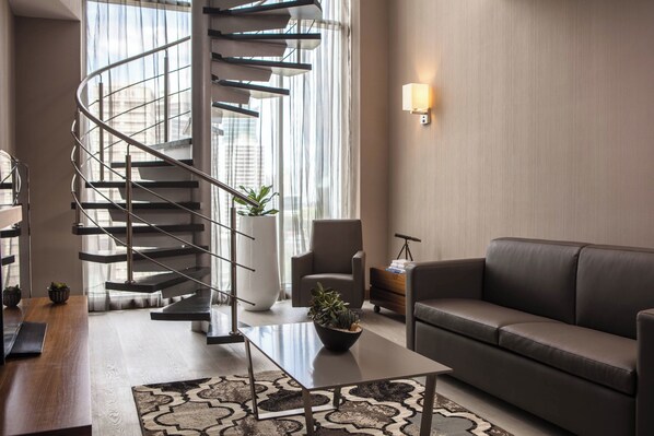 Uma sala de estar moderna com uma escada em espiral, um sofá de couro, uma mesa de centro e um vaso com planta.