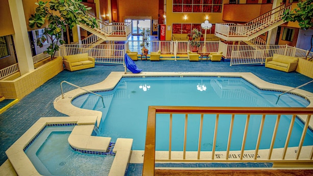 Piscina interior com vários níveis, áreas de estar e um letreiro da Coca-Cola.