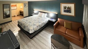 Quarto de hotel com uma cama, um sofá de couro marrom, uma escrivaninha e uma cadeira.