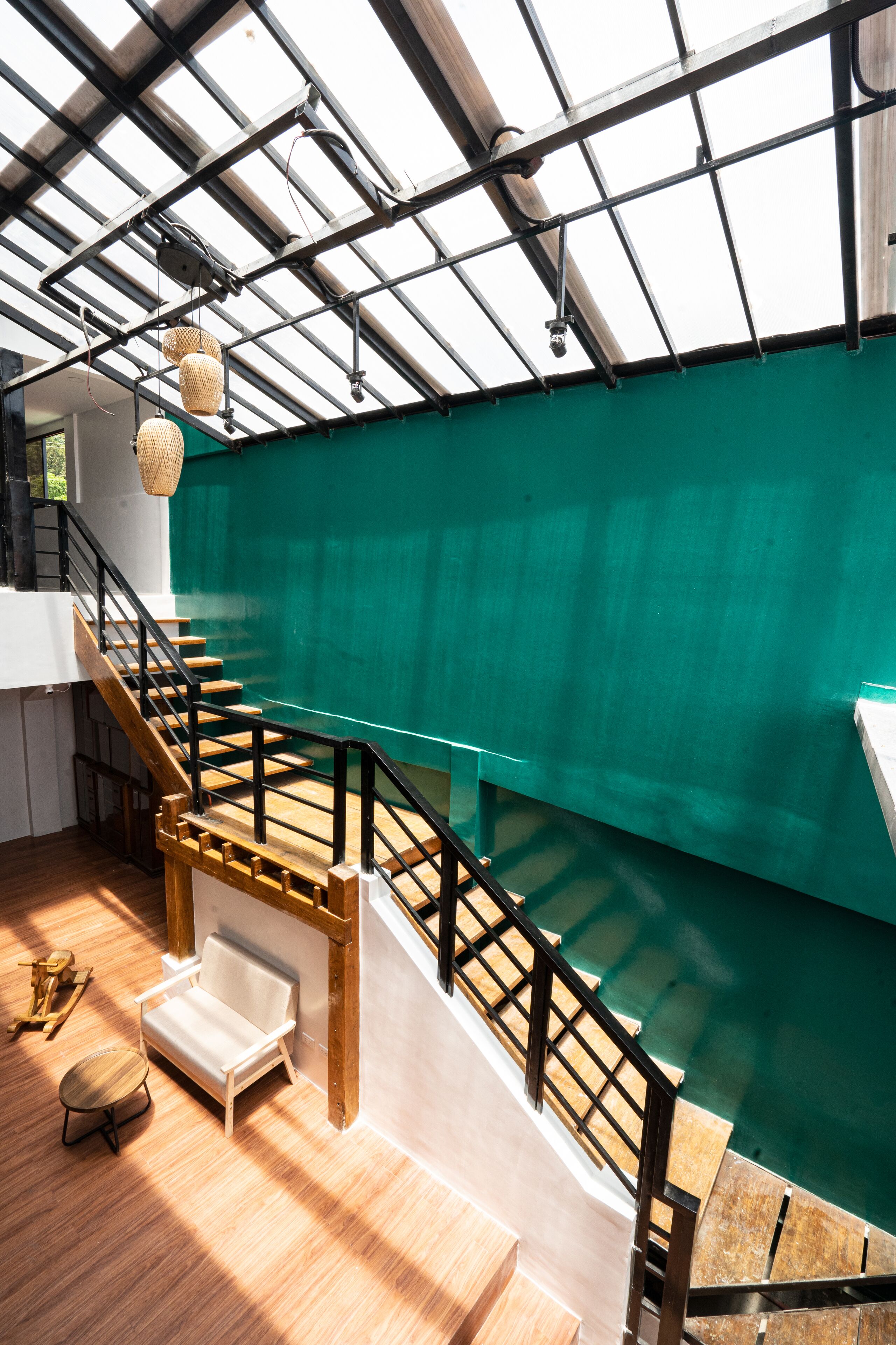 Interior moderno com escada de madeira, parede verde e sofá branco.