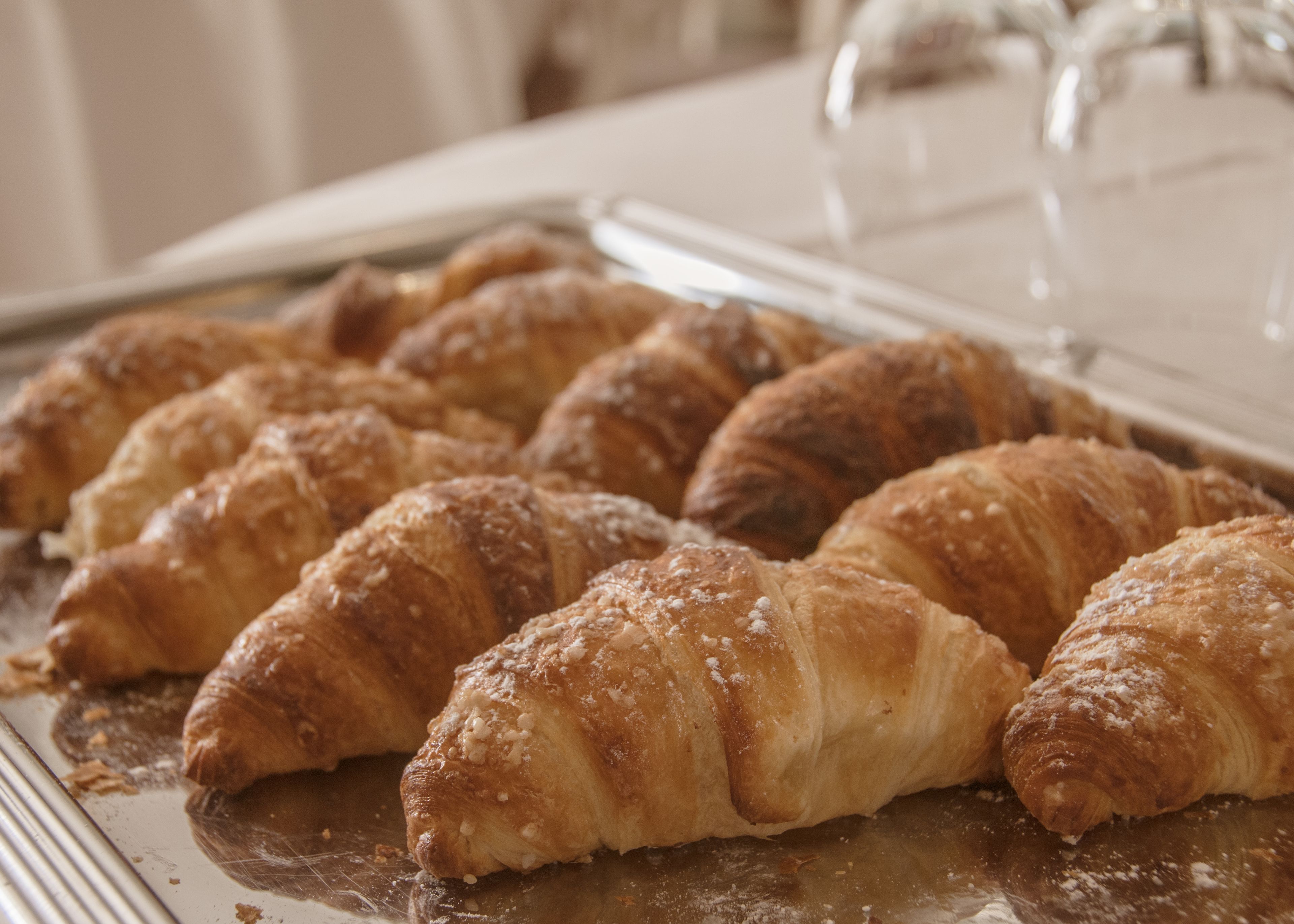 Uma bandeja de croissants recém-assados polvilhados com açúcar de confeiteiro.