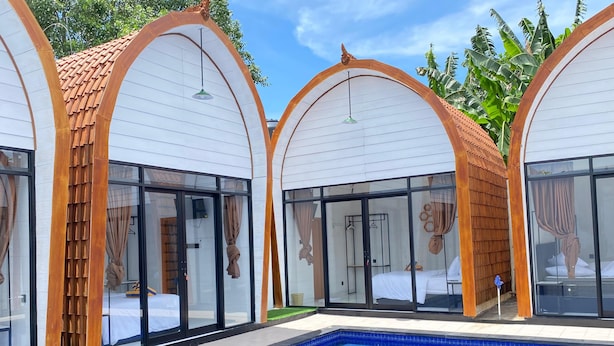 Um hotel moderno com piscina, apresentando estruturas de madeira arqueada e portas de vidro.