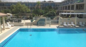 Piscina com espreguiçadeiras e escadaria que leva a um nível superior.
