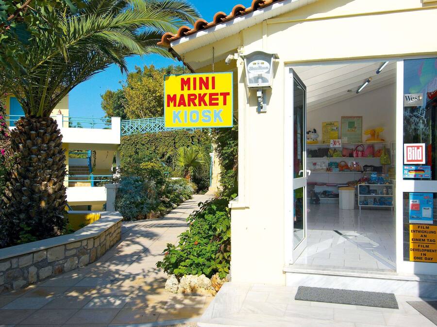 Fachada com uma placa indicando "MINI MARKET KIOSK" e uma vitrine com diversos produtos.