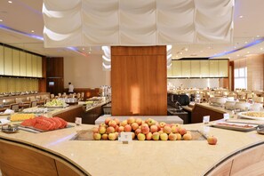 Uma área de buffet com diversos alimentos e uma grande exposição de maçãs.