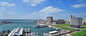 Paisagem urbana costeira com um porto de iates, edifícios modernos e céu claro.