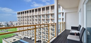 Um hotel com vários andares, varandas, área de estar externa e piscina.