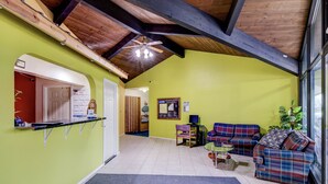Uma sala de estar com parede verde, teto de madeira, sofá xadrez e uma pequena mesa.