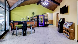 Um restaurante com teto de madeira, paredes verdes, uma máquina de vendas automática e um quiosque de autoatendimento.